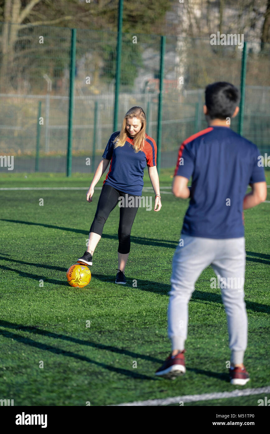 school students having a football lesson to improve their skills at ...