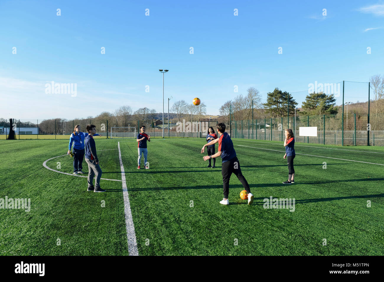school students having a football lesson to improve their skills at ...