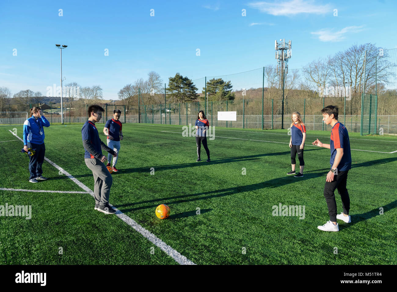 school students having a football lesson to improve their skills at ...