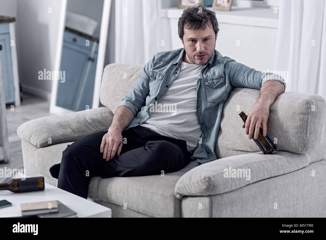 Thoughtful man holding a bottle and realizing his mistake Stock Photo ...