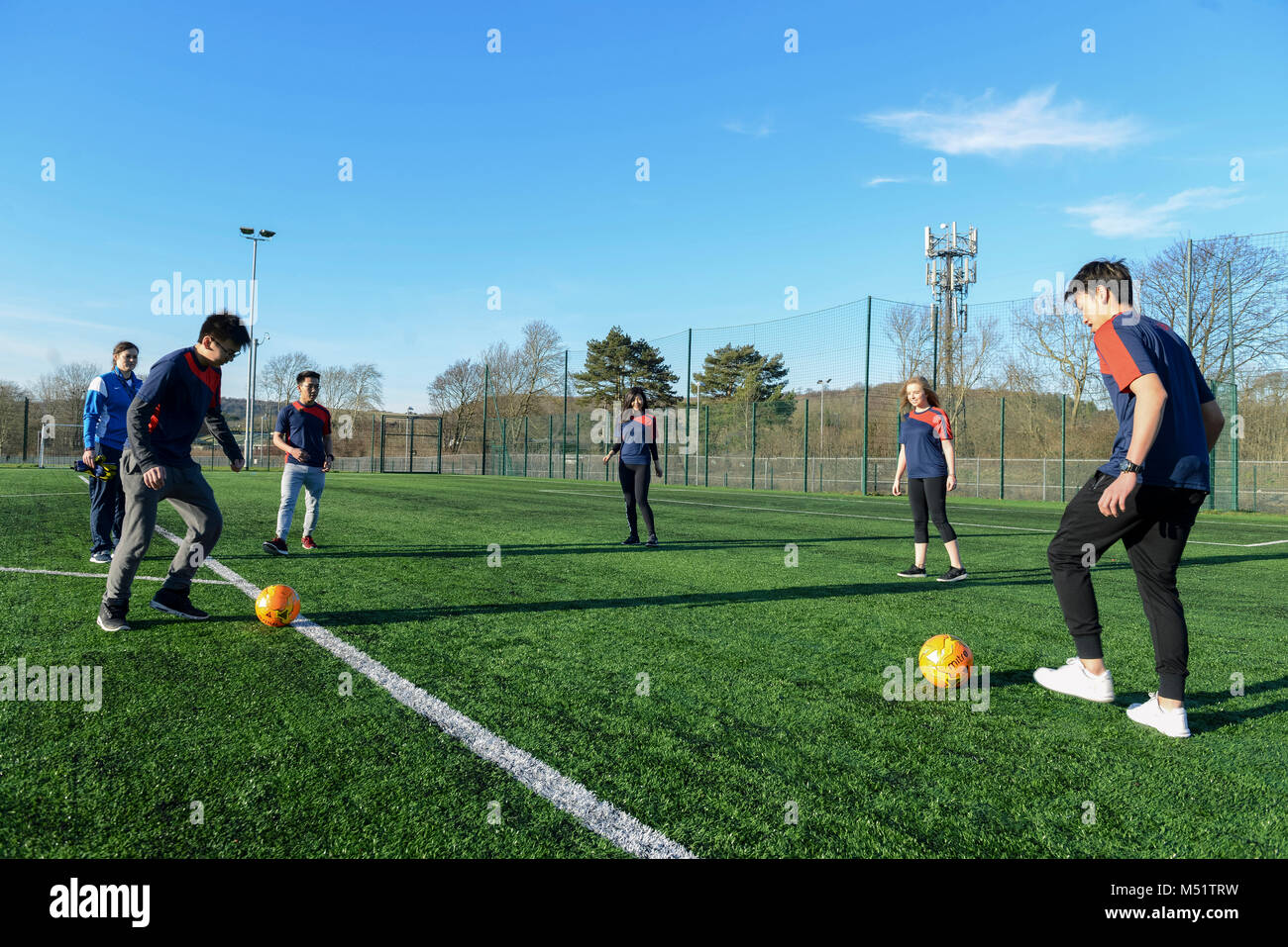 school students having a football lesson to improve their skills at ...
