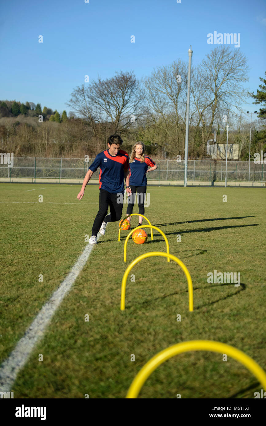school students having a football lesson to improve their skills at ...