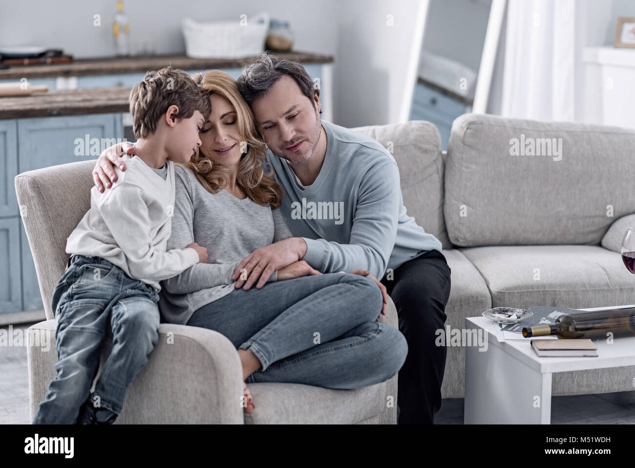 Peaceful man hugging his kind wife and son and feeling glad Stock Photo ...