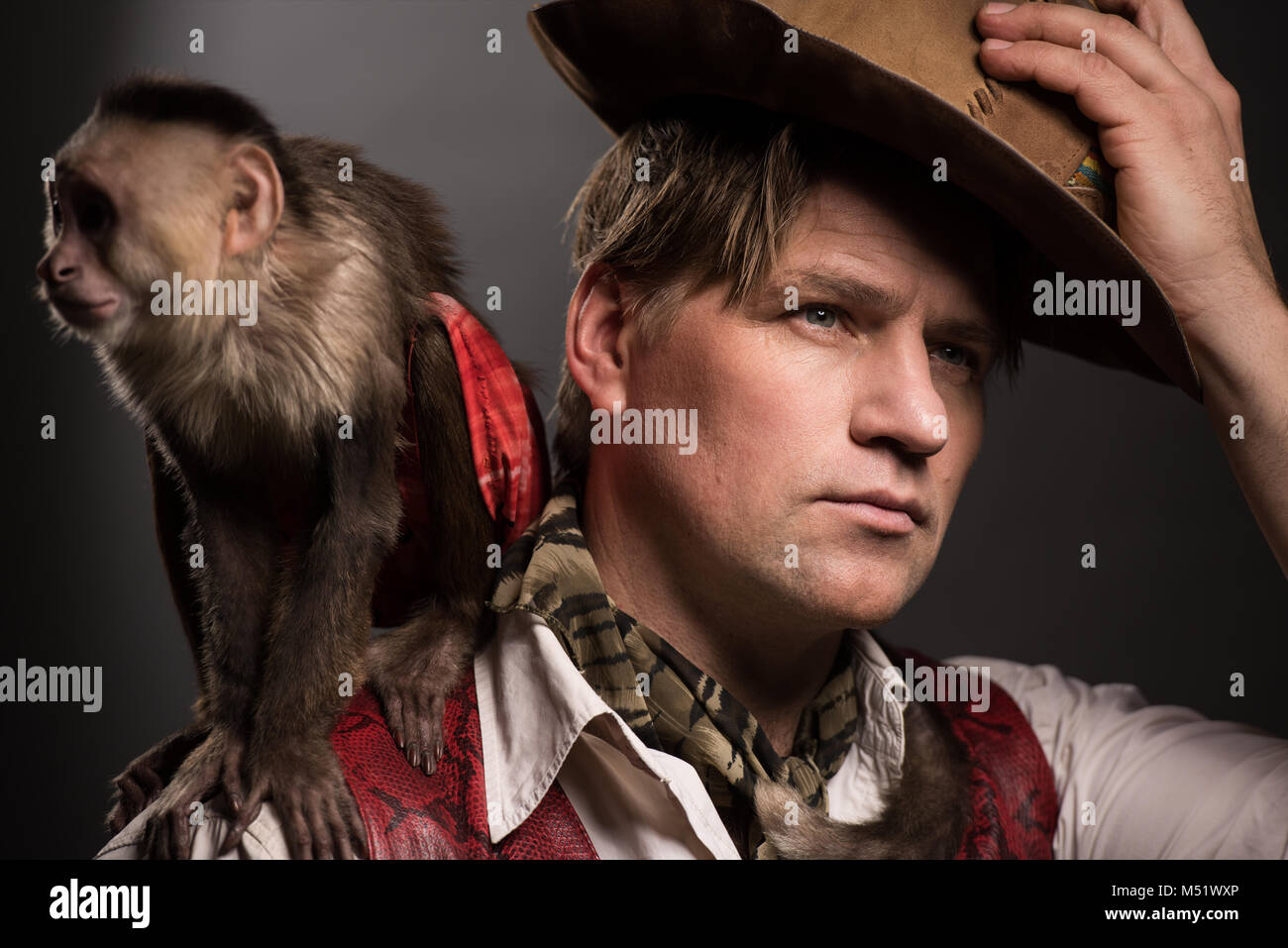 Mature man adventurer in costume of traveler with his monkey companion ...