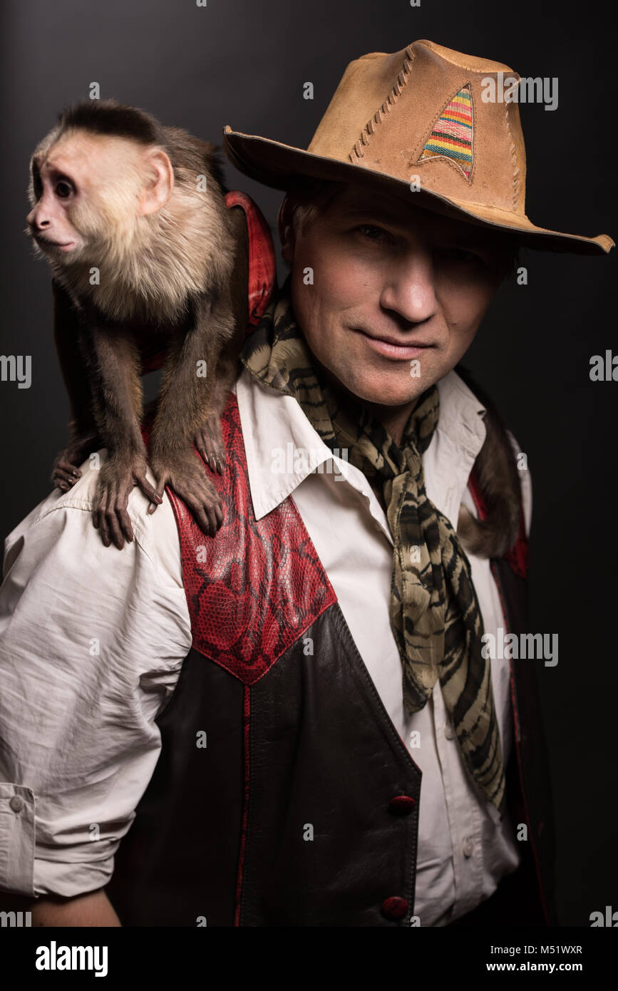 Mature man adventurer in costume of traveler with his monkey companion ...
