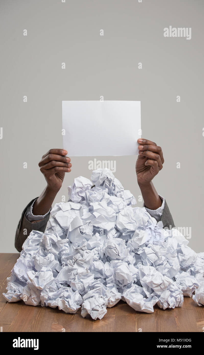 African business woman under crumpled pile of papers with raised hand ...