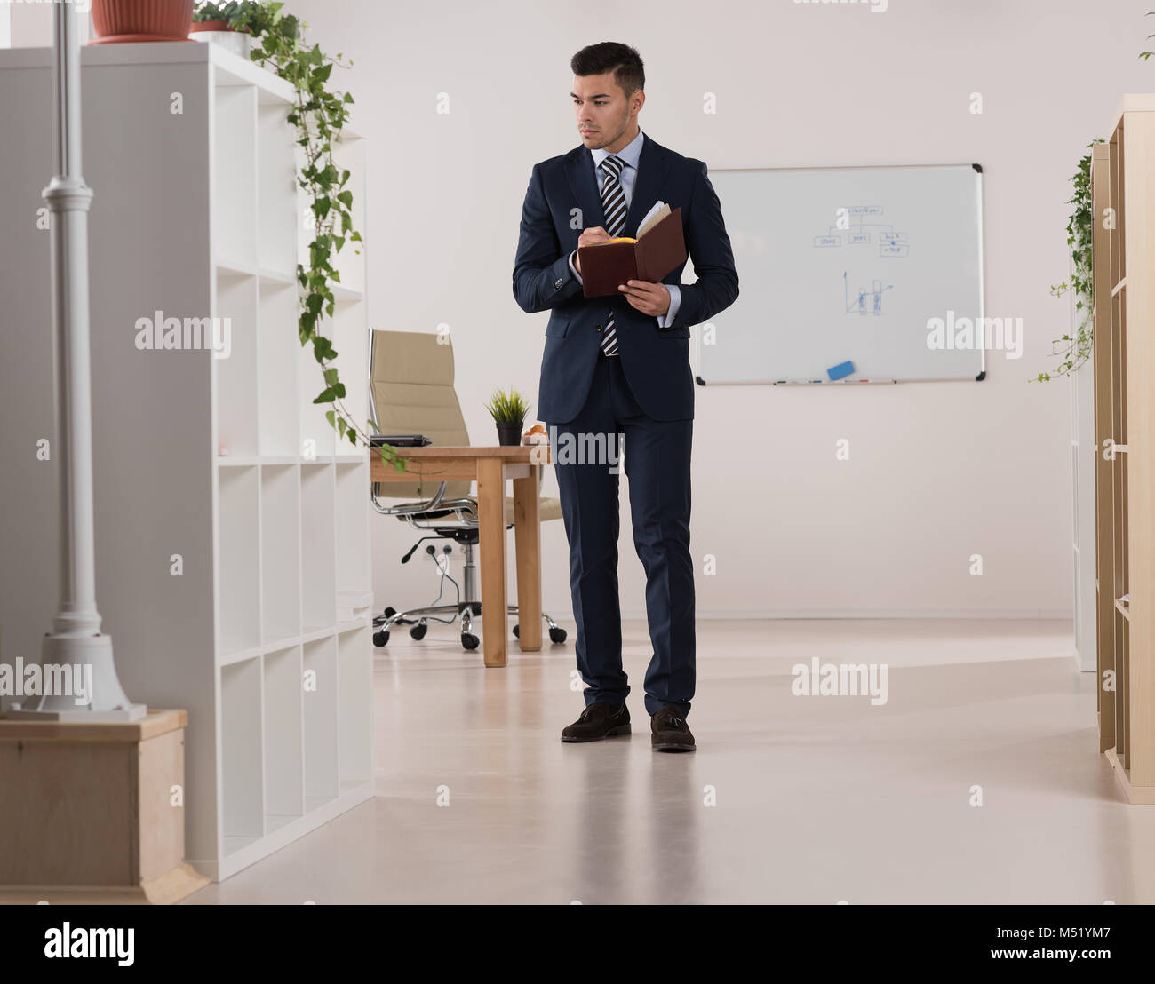 Portrait of a busy businessman taking notes and writing something in ...