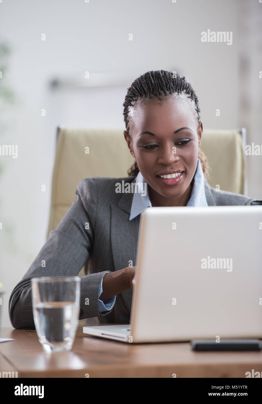 Pretty african business woman working on laptop in office Stock Photo ...