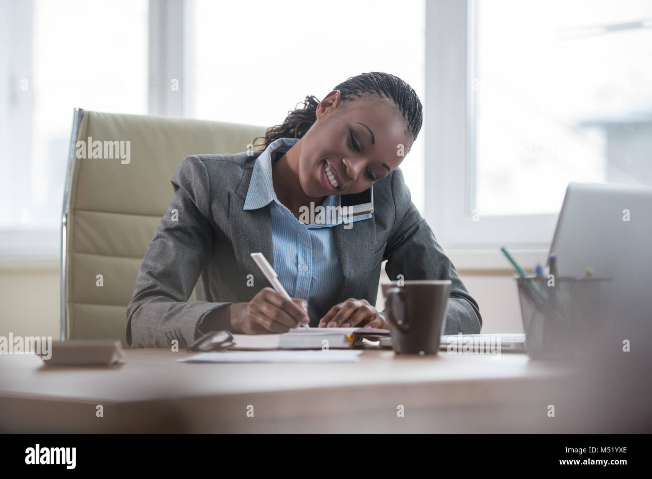Portrait of busy business woman or secretary writing and typing in ...