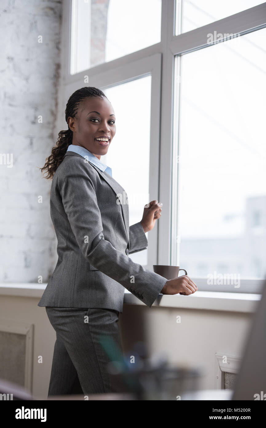 Portrait of smiling african business woman at her office with coffee ...