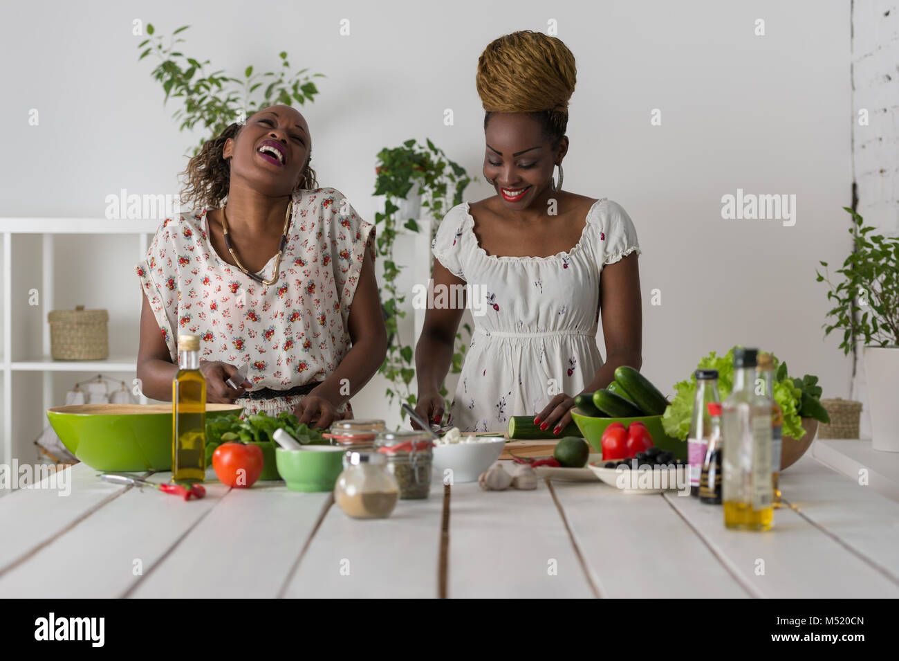 Two african women cooking in kitchen making healthy food salad with ...