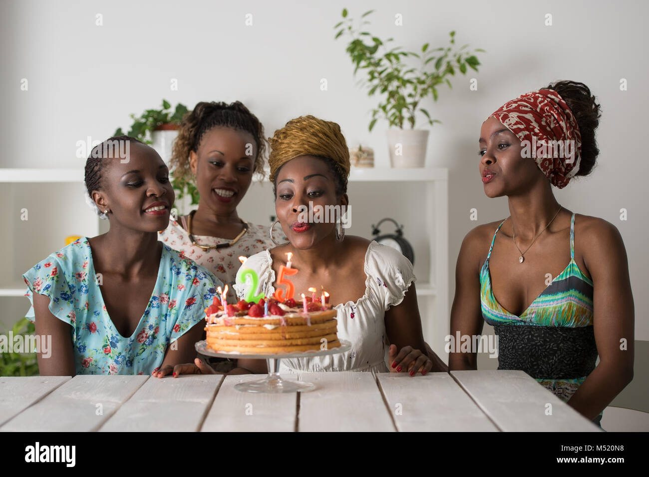 Portrait of joyful african girl looking at birthday cake surrounded by ...