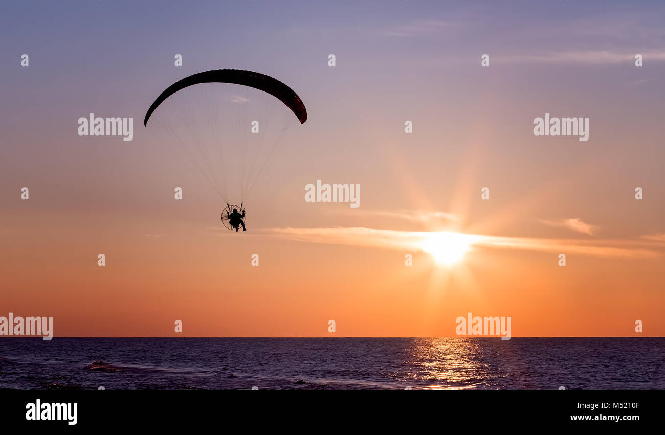 Paraglider flying at sunset Stock Photo - Alamy