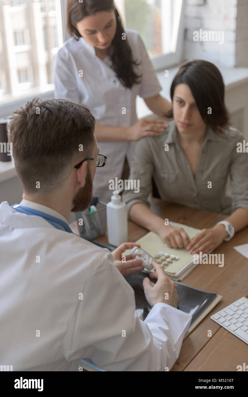 At doctor office. Doctor talking to patient after tests. Nurse standing ...