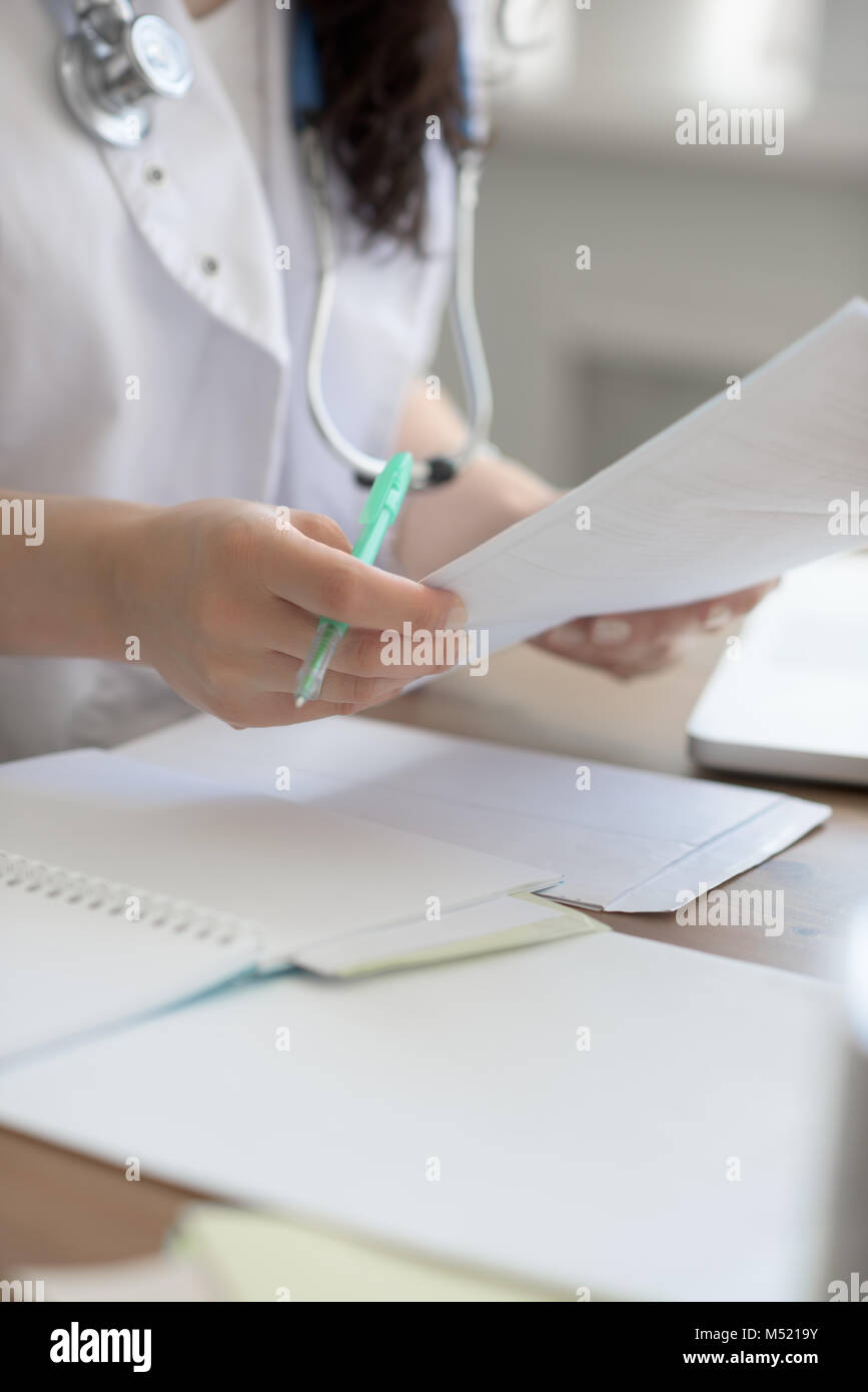 Female doctor taking notes during looking at patient medical tests at ...