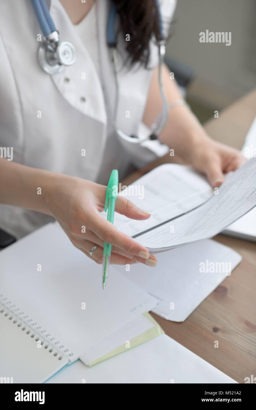 Female doctor taking notes during looking at patient medical tests at ...