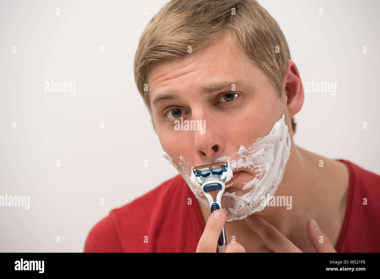Happy young adult man shaving his face over white background Stock ...