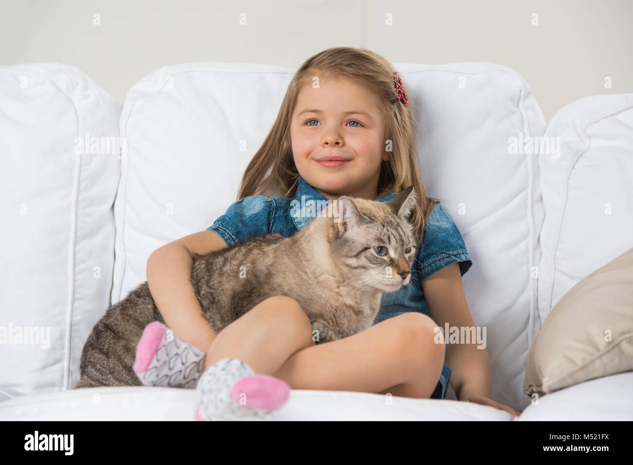Cute little girl hugging tabby cat with love, looking away Stock Photo ...