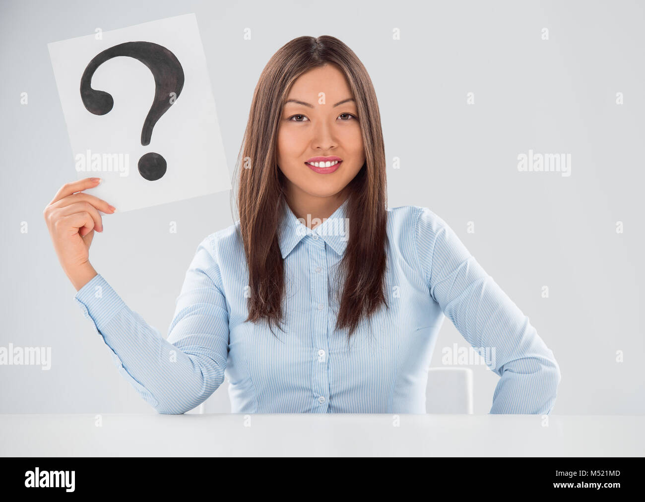 Portrait of business woman with question mark on placard over gray ...