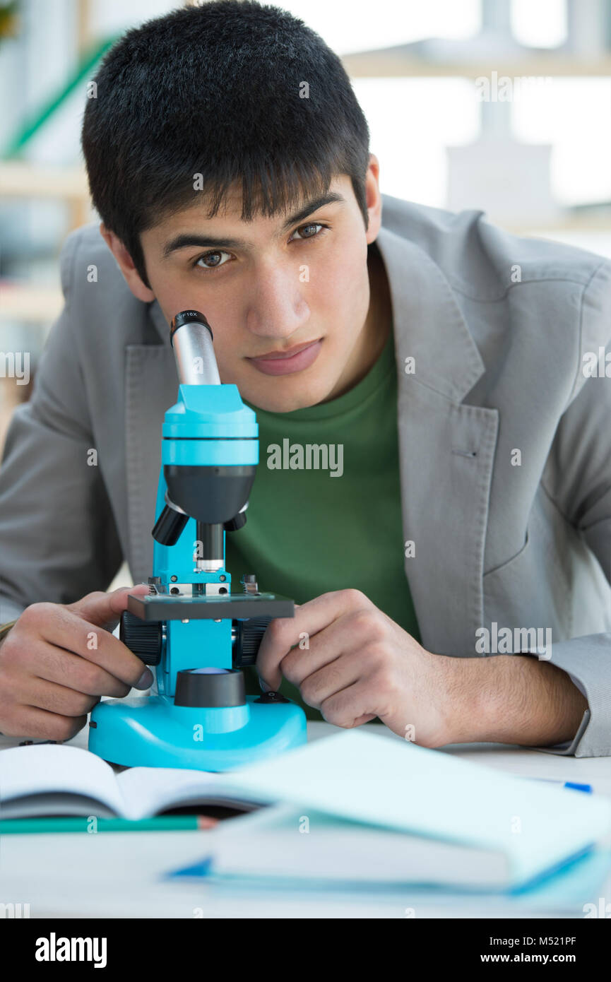 Male student in laboratory looking at camera while working with ...