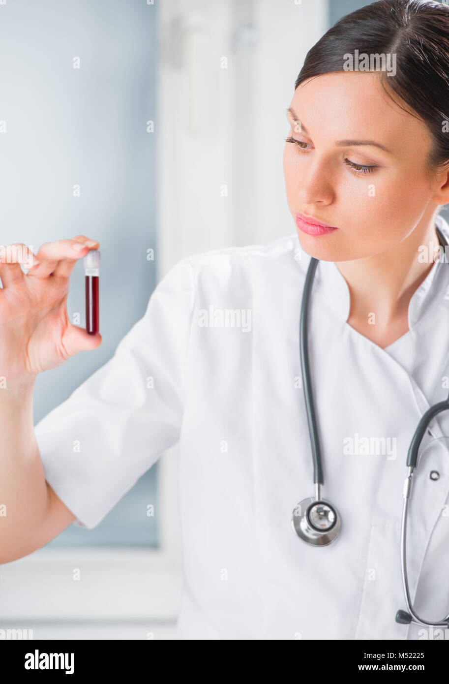 Portrait of pretty female laboratory assistant analyzing a blood sample ...