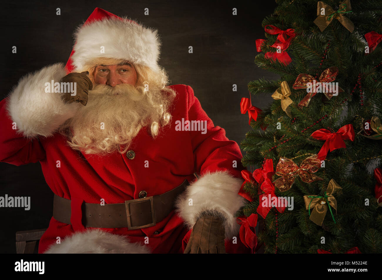 Santa Claus decorating Christmas tree in dark room Stock Photo - Alamy