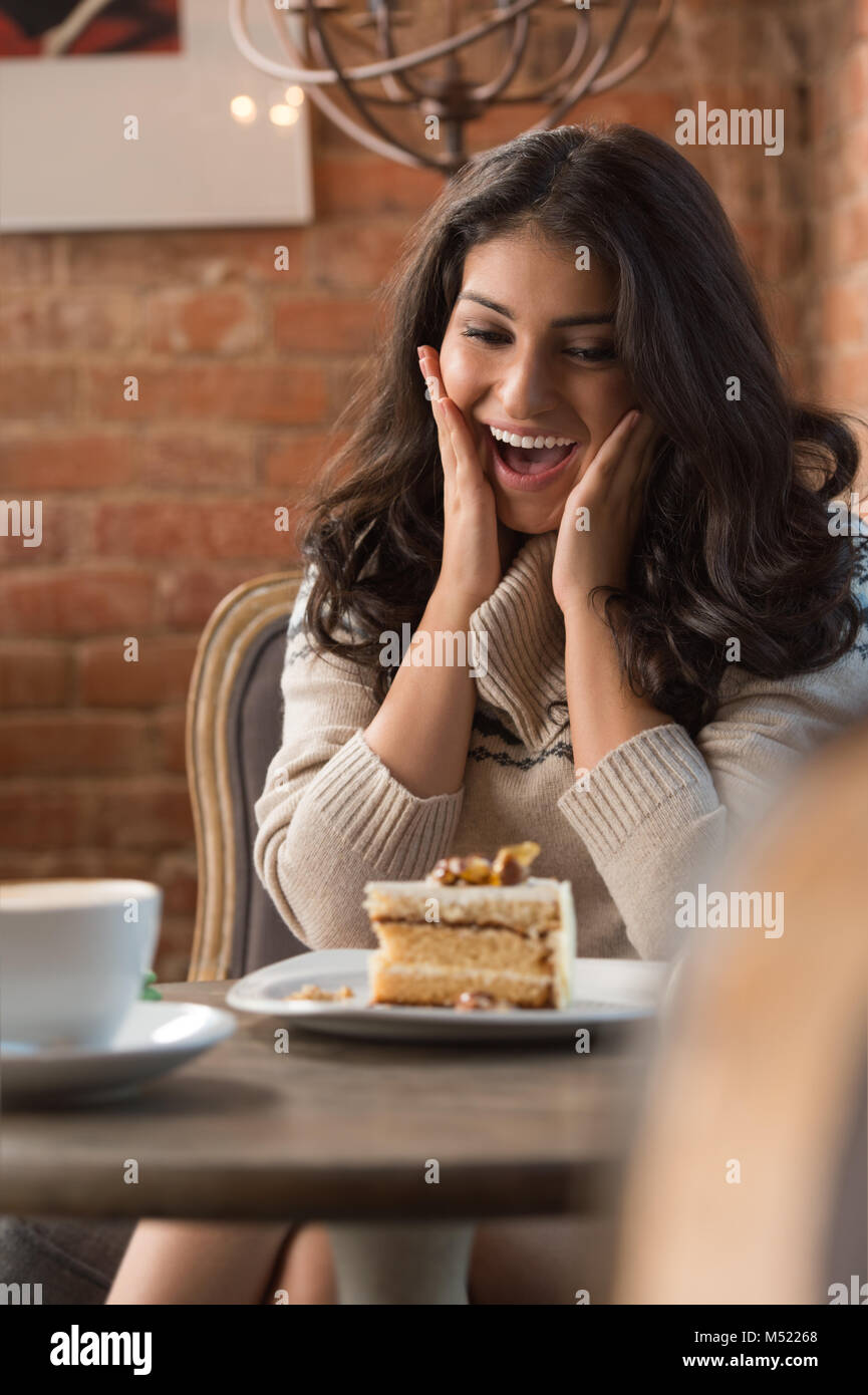 Young woman happy with her cake in a cafe indoors. Shallow depth of ...