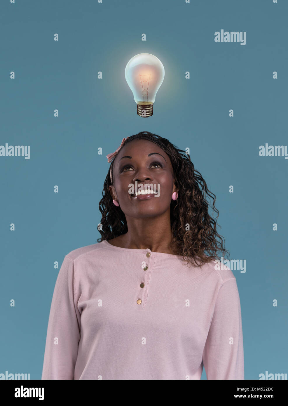 Pretty young african lady standing and thinking with light bulb overhead. Idea concept Stock ...