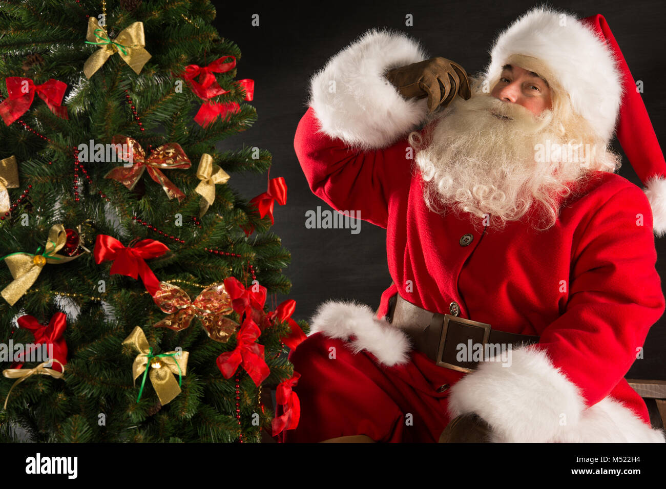 Santa Claus standing near Christmas tree in dark room Stock Photo - Alamy