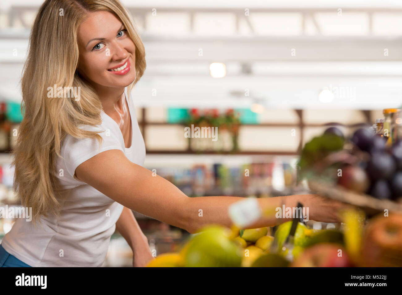 Casual woman grocery shopping at organic food section and looking happy ...