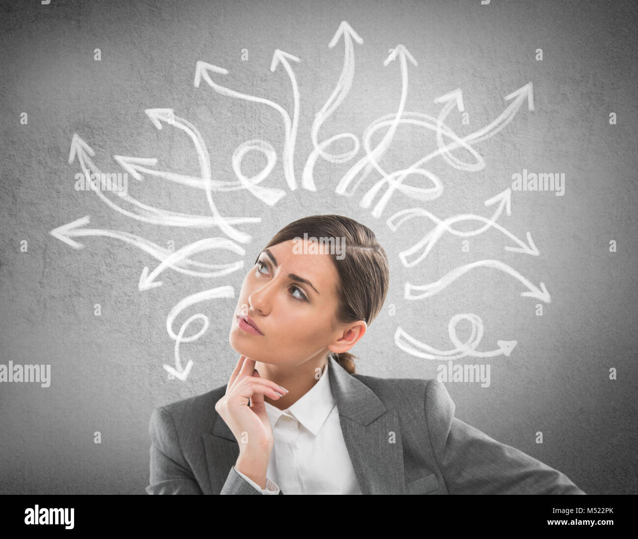 Serious, young businesswoman looking at many twisted arrows on the ...