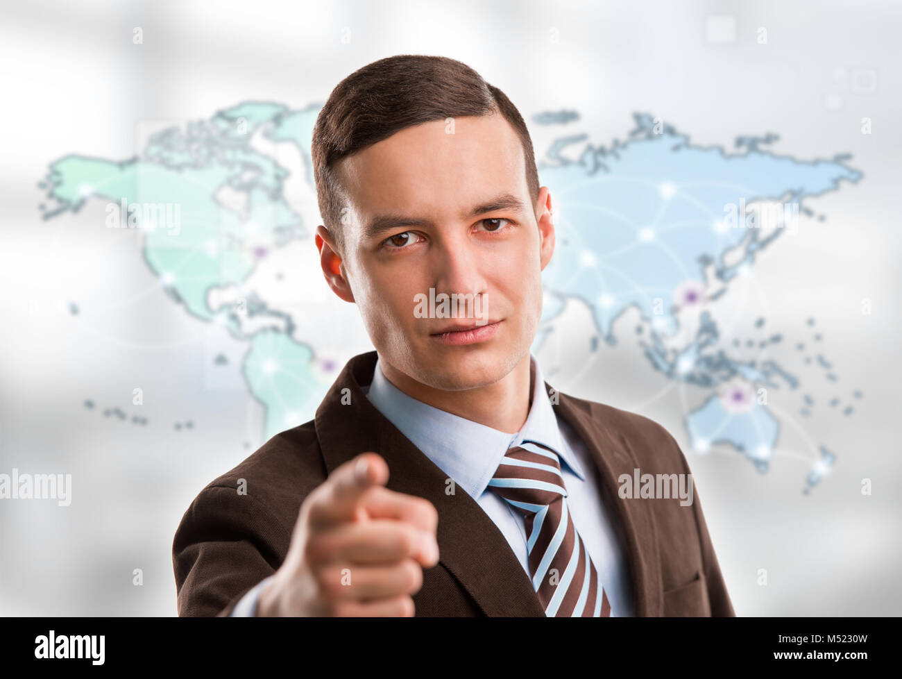 Portrait of young man standing in front of big world map and looking at ...