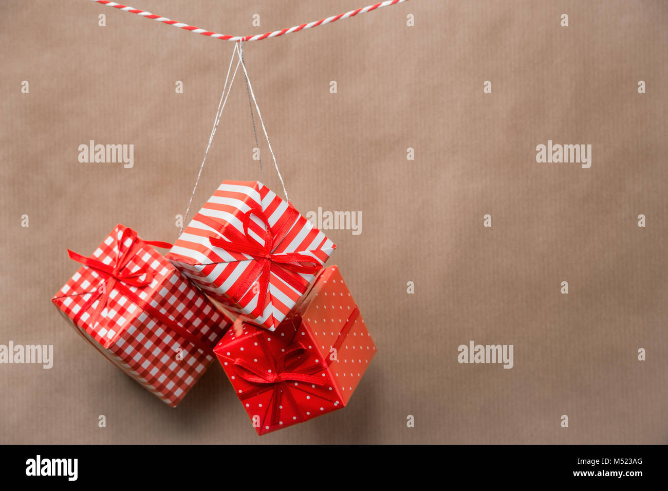 Red gift boxes hanging on a ribbon. Old brown paper background Stock ...