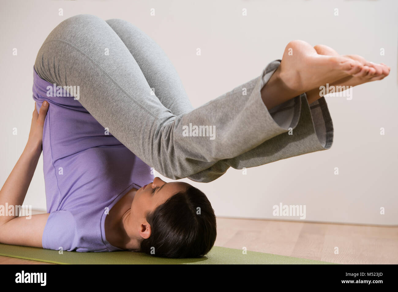 Woman in a traditional stretching yoga pose at home or gym Stock Photo ...