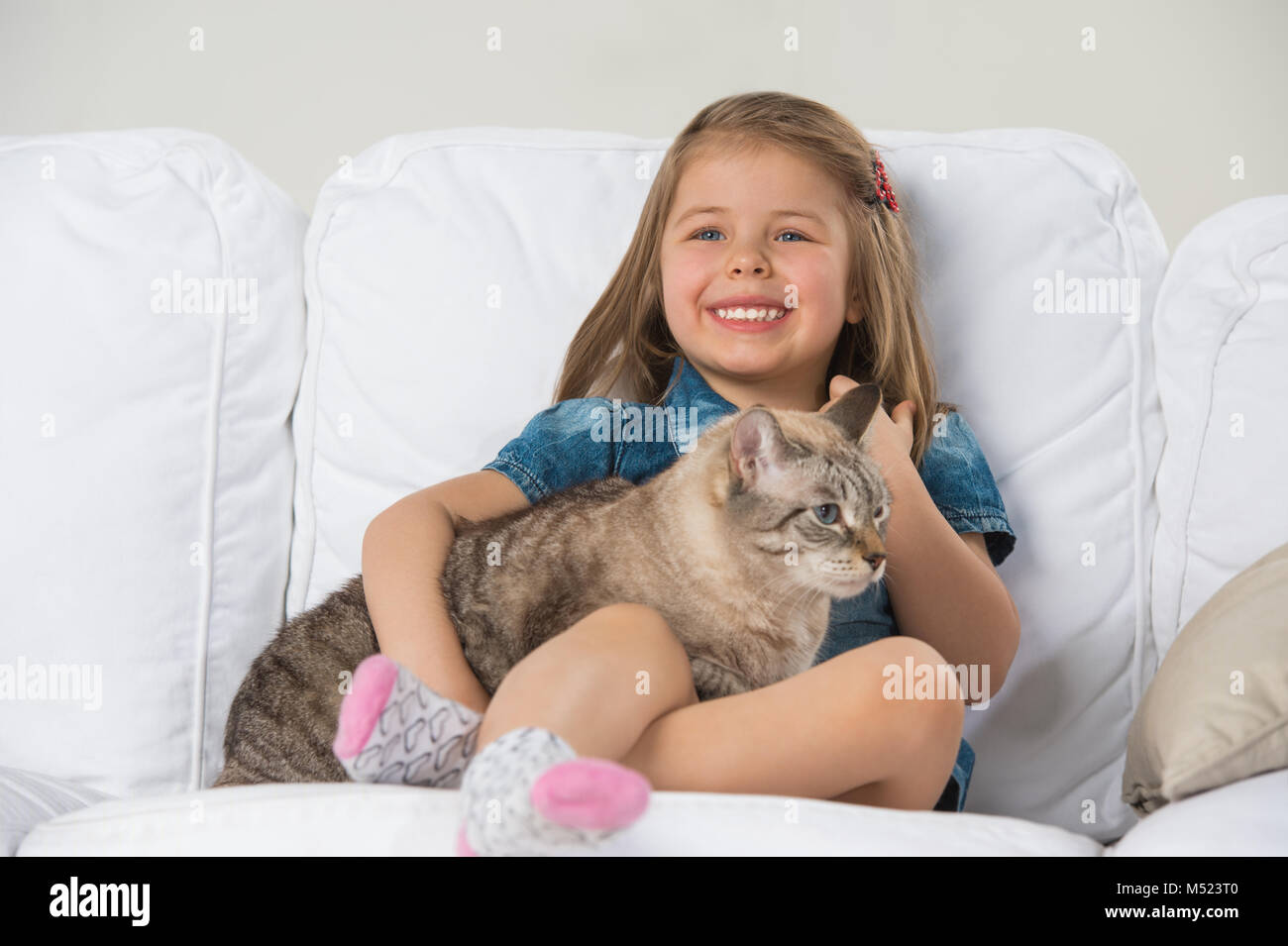 Cute little girl hugging tabby cat with love, looking away Stock Photo ...