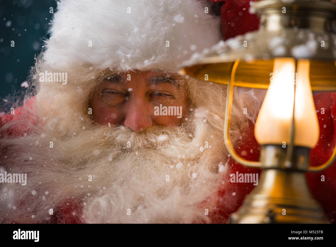 Santa Claus is holding a shining lantern while sneaking to his home ...