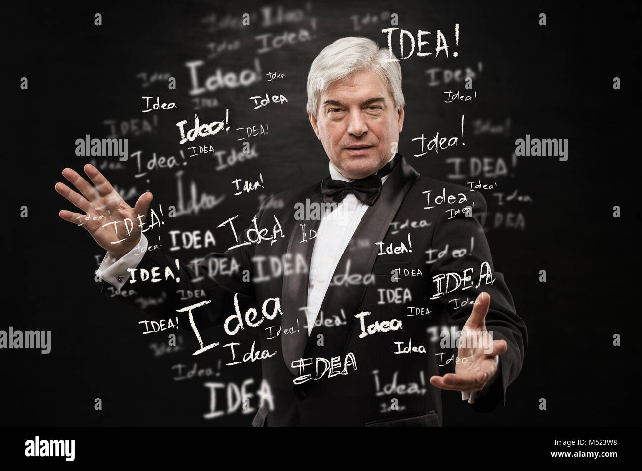 Idea concept. Mature business man standing on black background with ...