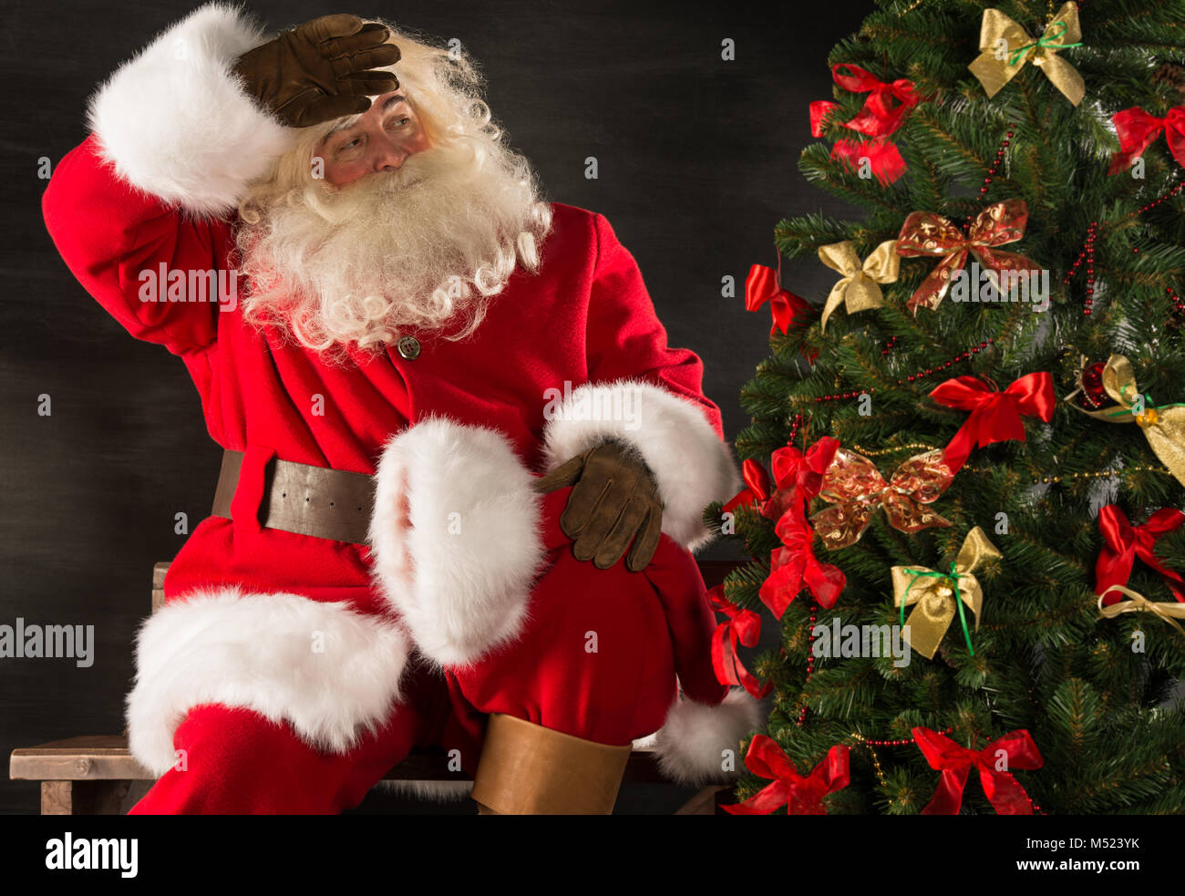Santa Claus decorating Christmas tree in dark room Stock Photo - Alamy