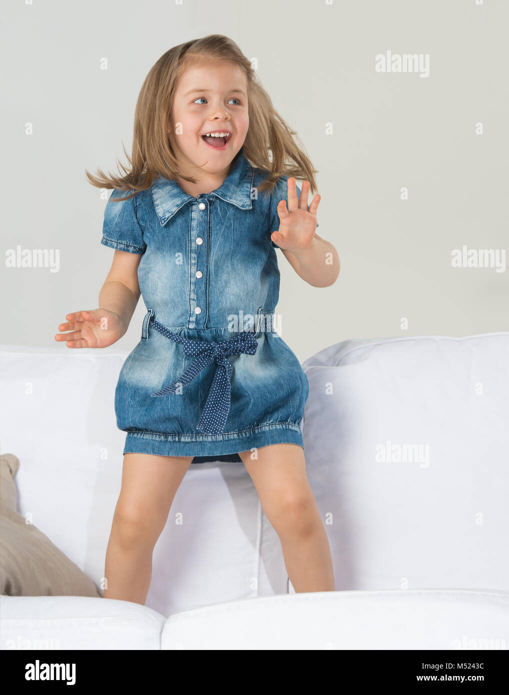 Adorable little girl jumping at home on sofa Stock Photo - Alamy