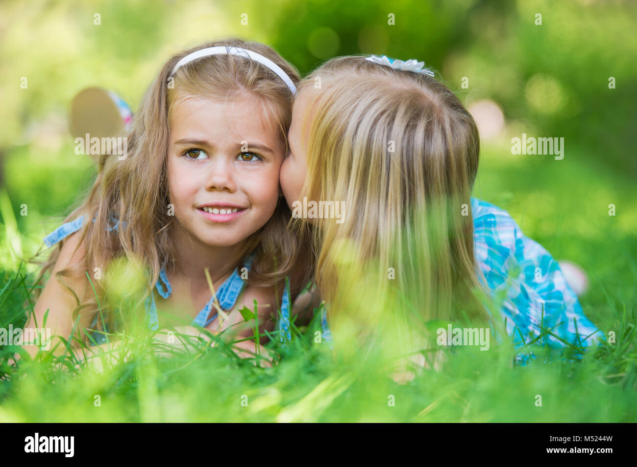 Happy children relaxing on green grass in summer park and talking ...