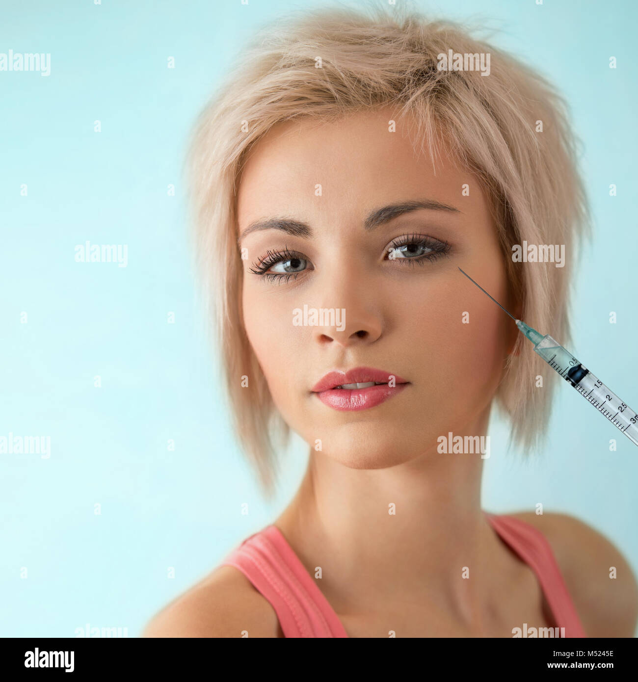 Beautiful woman gets an injection in her face on blue background Stock ...