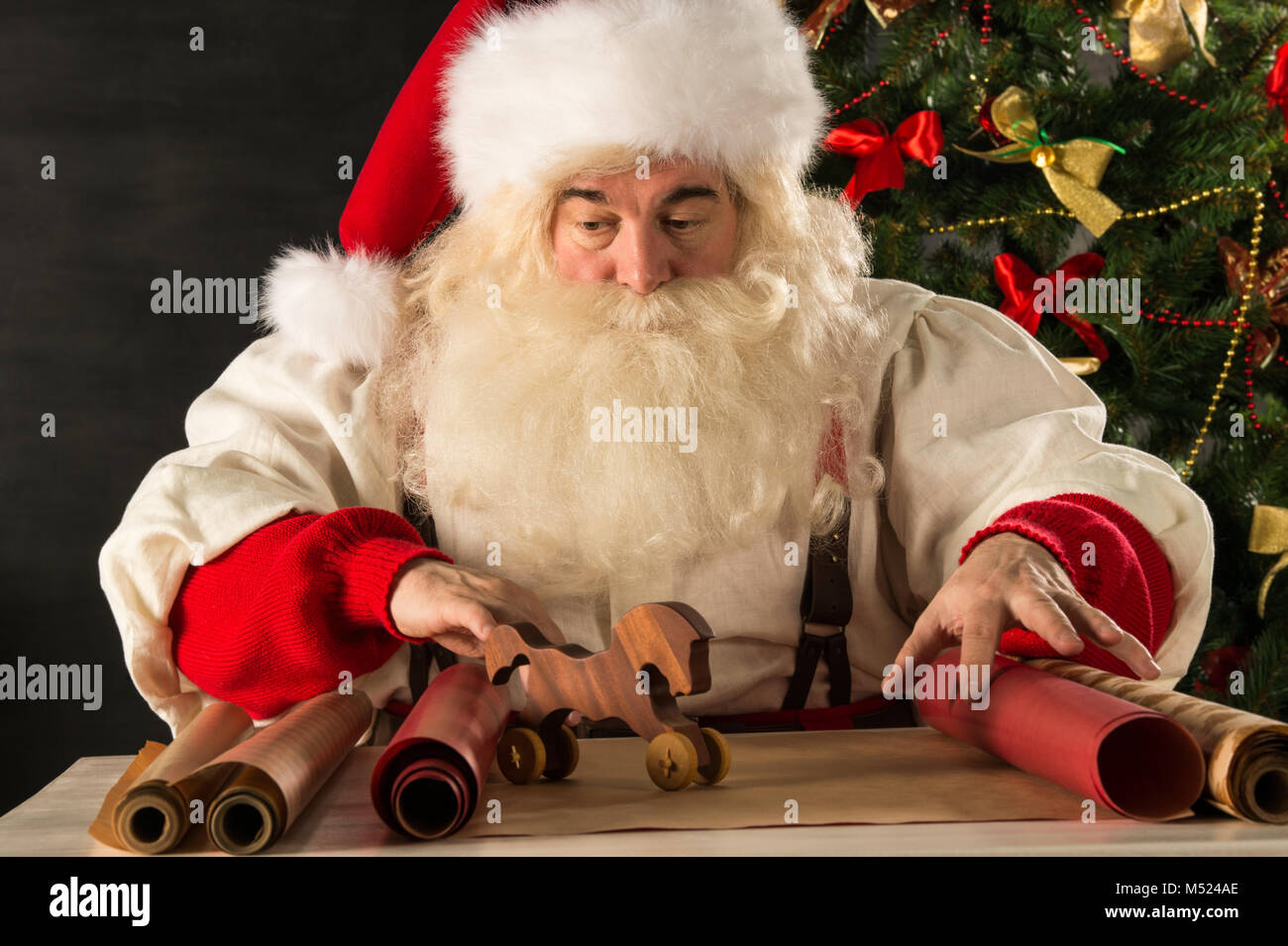 Santa Claus working - preparing and wrapping christmas gifts, toys ...