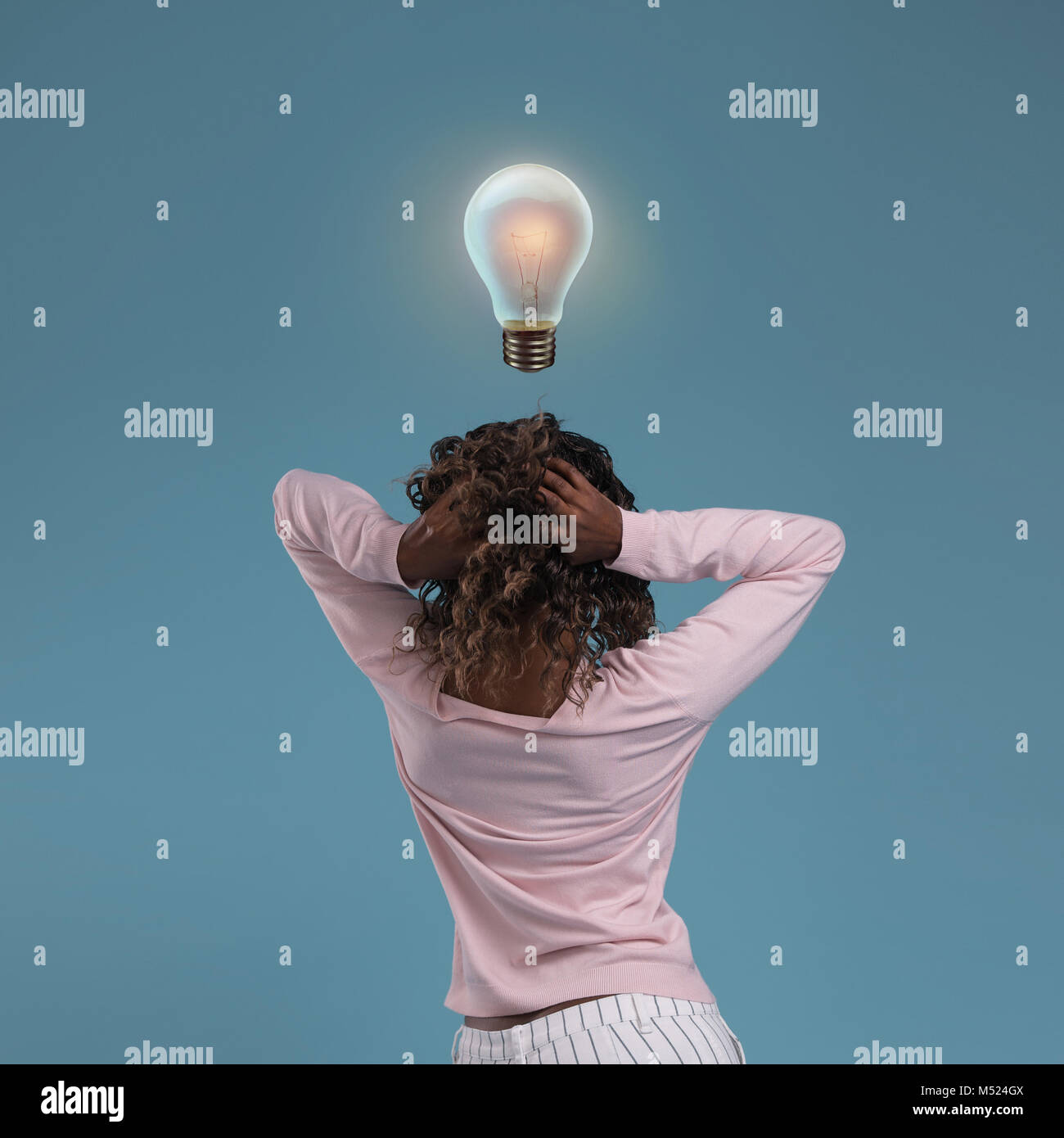 Pretty young african lady standing and thinking with light bulb ...