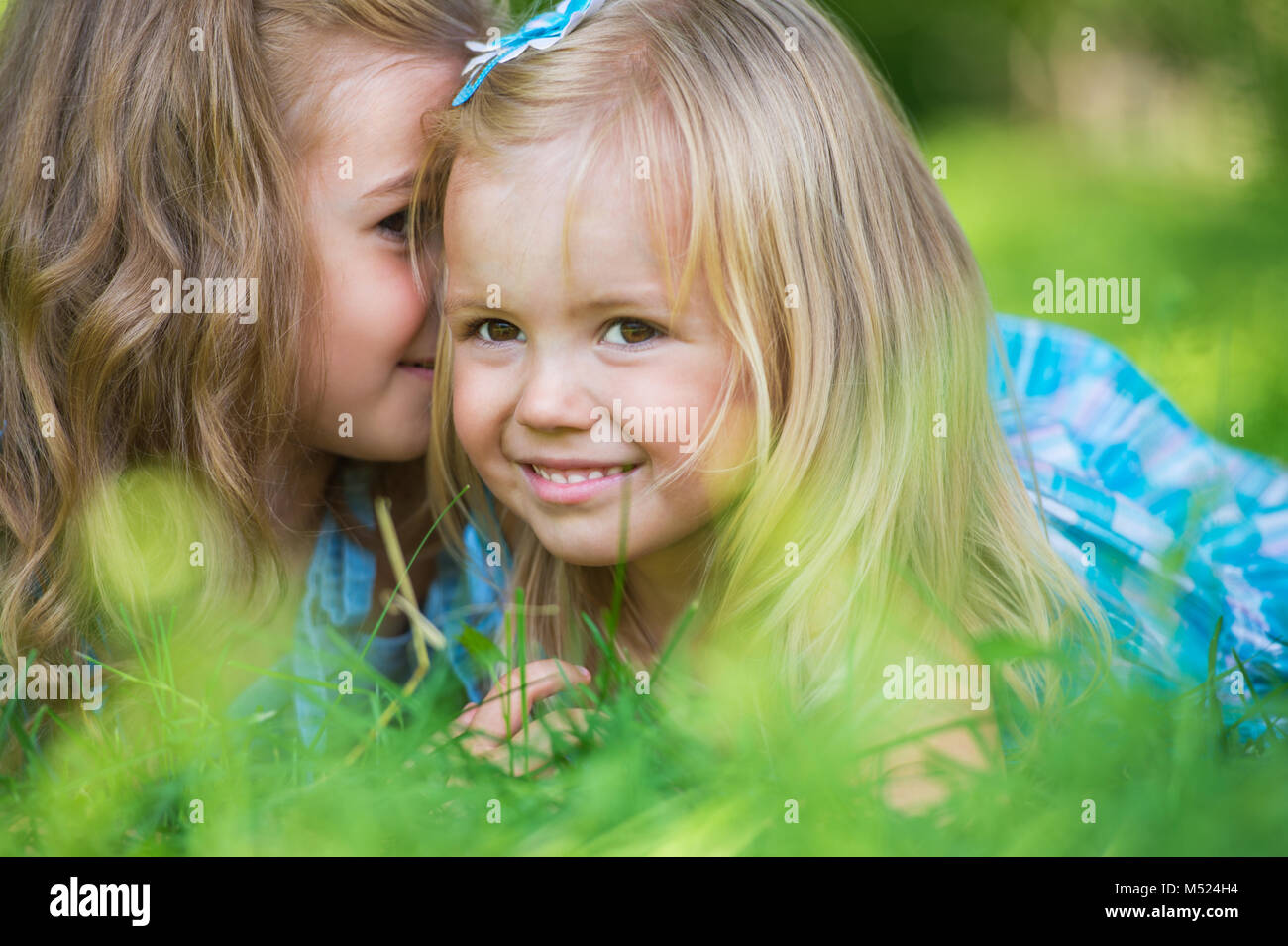 Happy children relaxing on green grass in summer park and talking ...