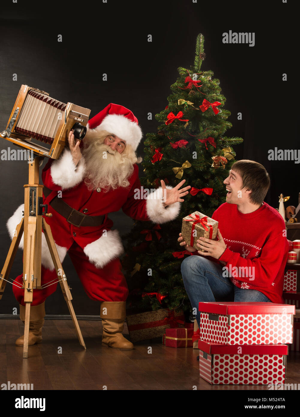 Santa Claus taking picture of cheerful man with old wooden camera at ...