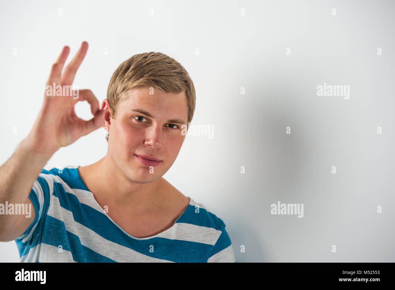 Closeup of good looking young man gesturing okay sign while leaning on ...