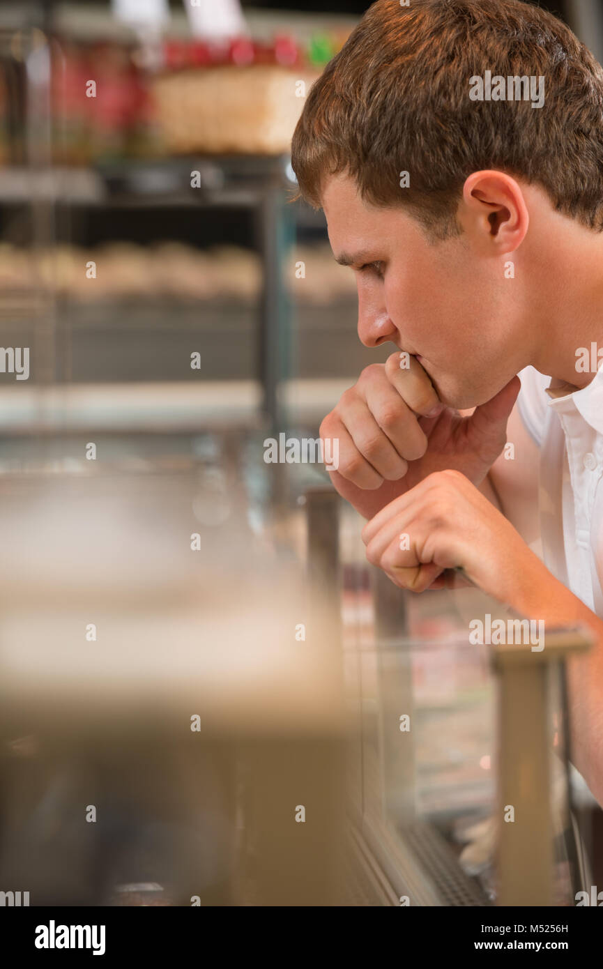 Handsome young man standing near supermarket showcase full of different ...