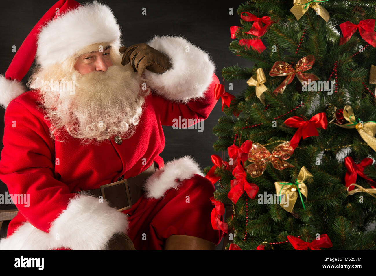 Santa Claus standing near Christmas tree in dark room Stock Photo - Alamy
