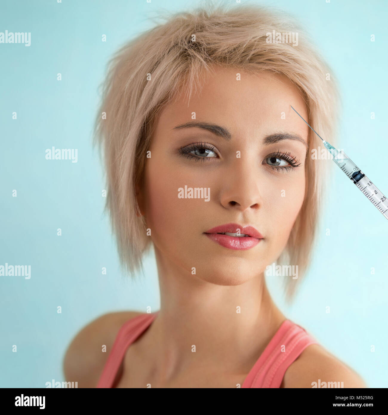 Beautiful woman gets an injection in her face on blue background Stock ...