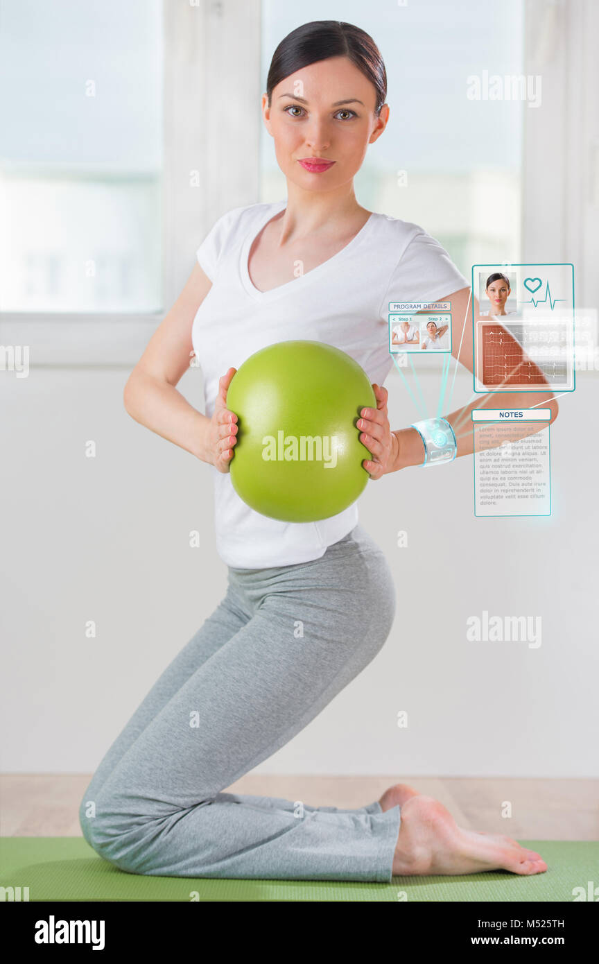 Woman doing exercise with ball wearing smart wearable device with ...